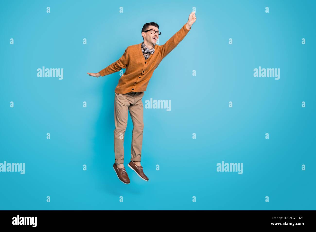 Full body photo of young excited man try catch umbrella jump up look ...