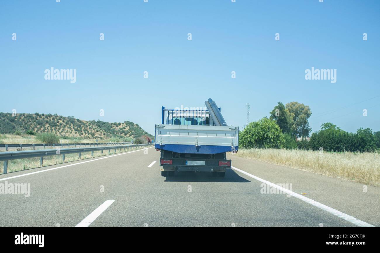 Driving behind open box truck loaded with pvc pipes. View from the ...