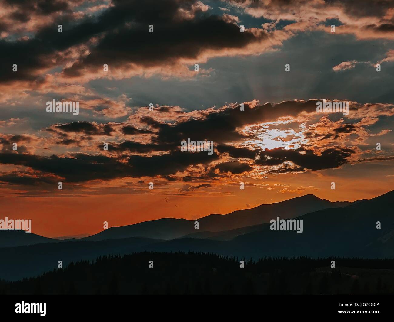 Breathtaking view of a dramatic cloudy sunset sky over the mountains ...