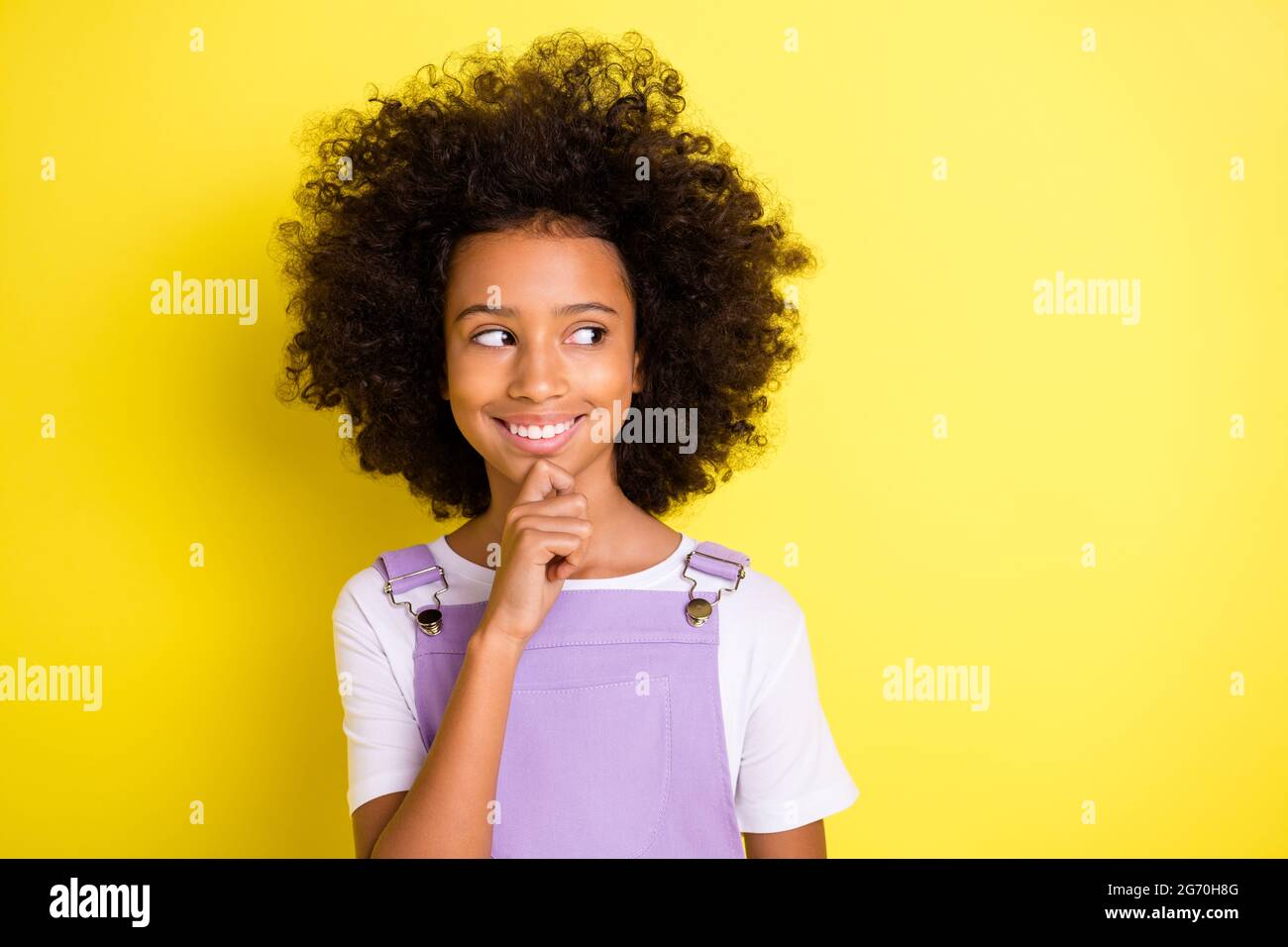 Photo of cunning playful small girl finger chin look side empty space ...