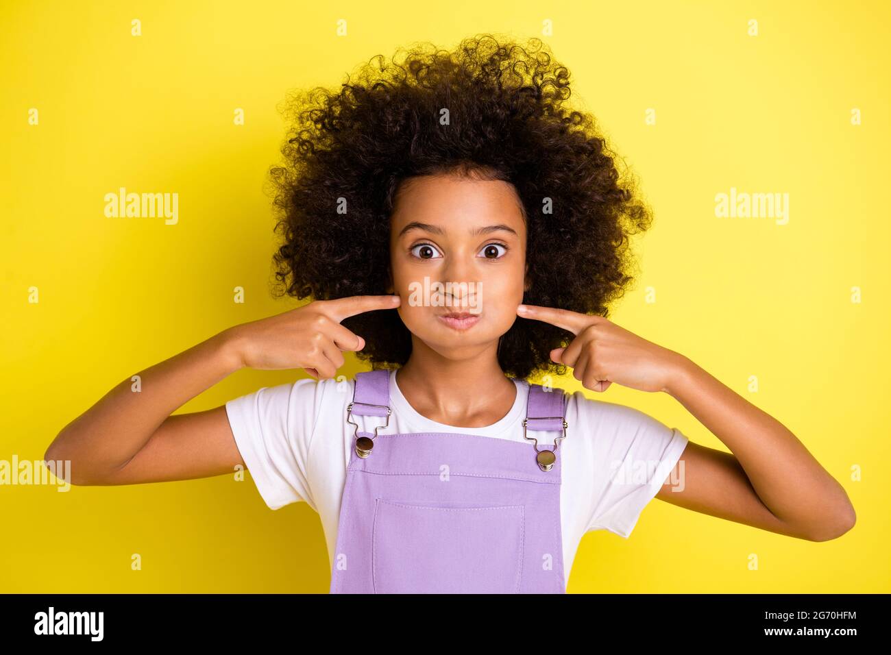Portrait of nice childish wavy-haired girl blowing touching cheeks ...