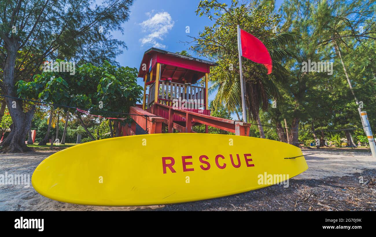 Red Lifeguard tower and yellow rescue board with red warning flag Stock ...