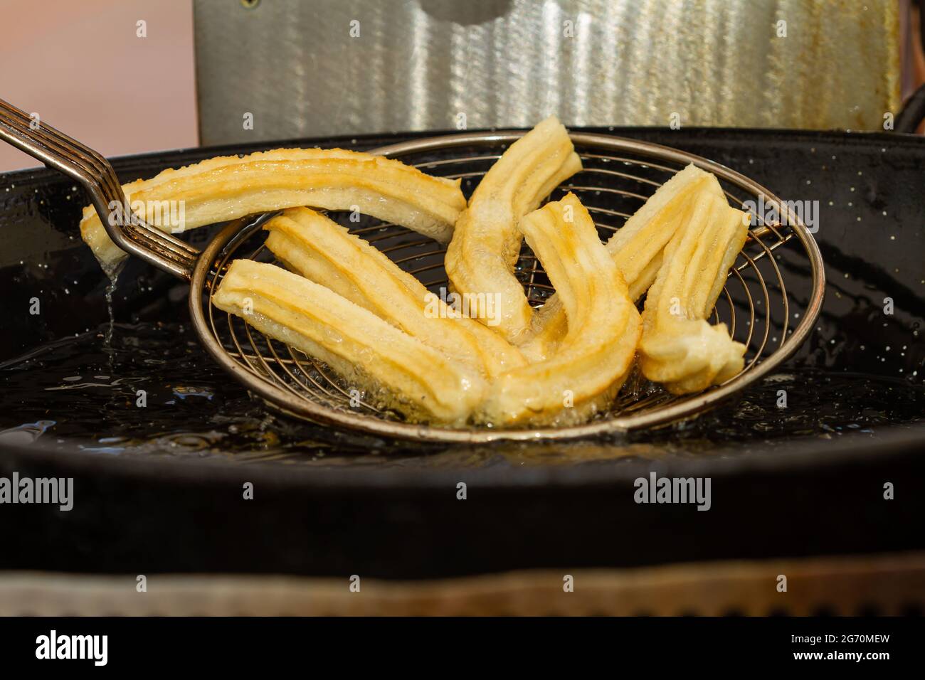 Churro dough frying in the hot oil pan Stock Photo - Alamy