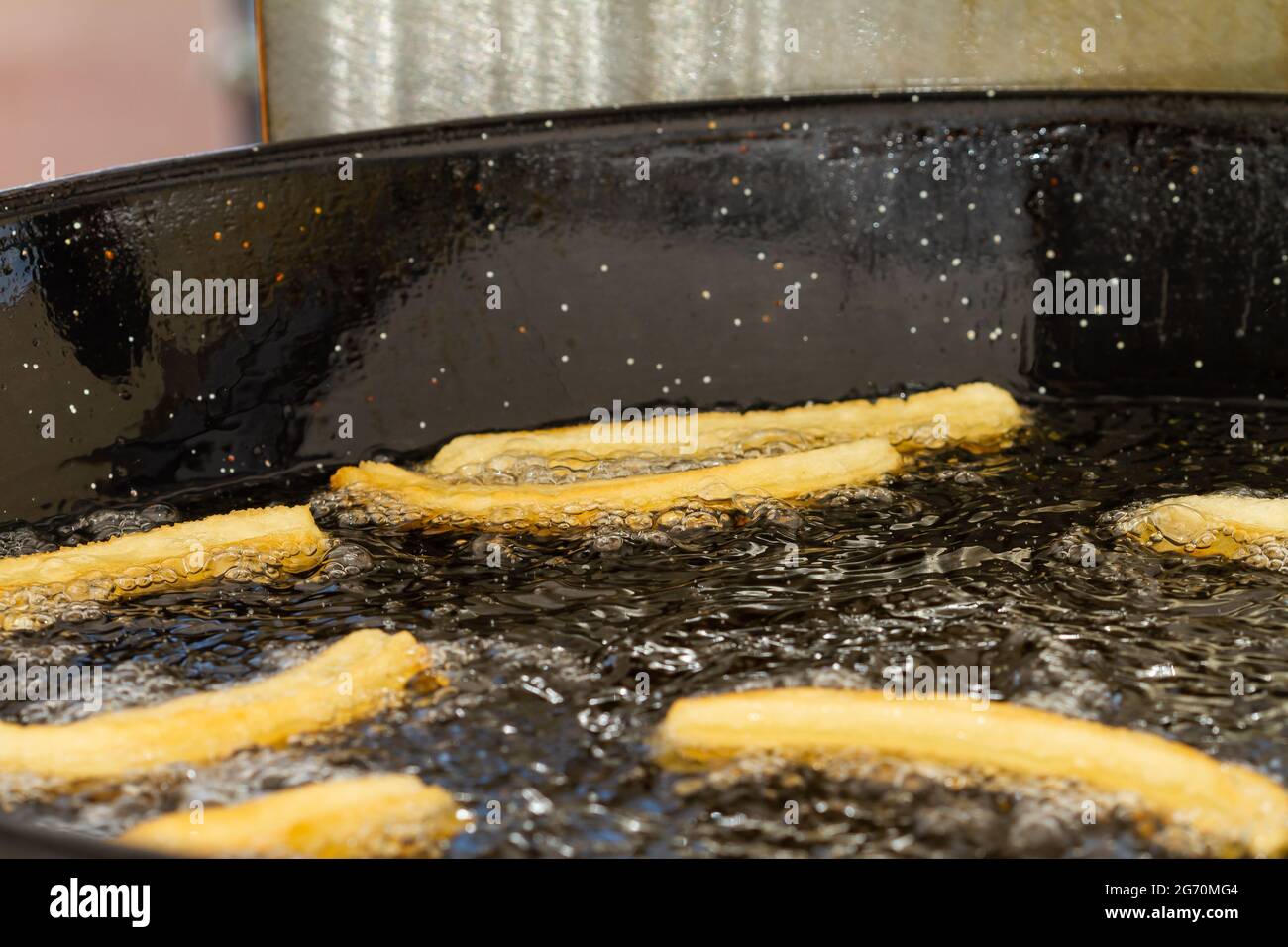 Churro dough frying in the hot oil pan Stock Photo - Alamy