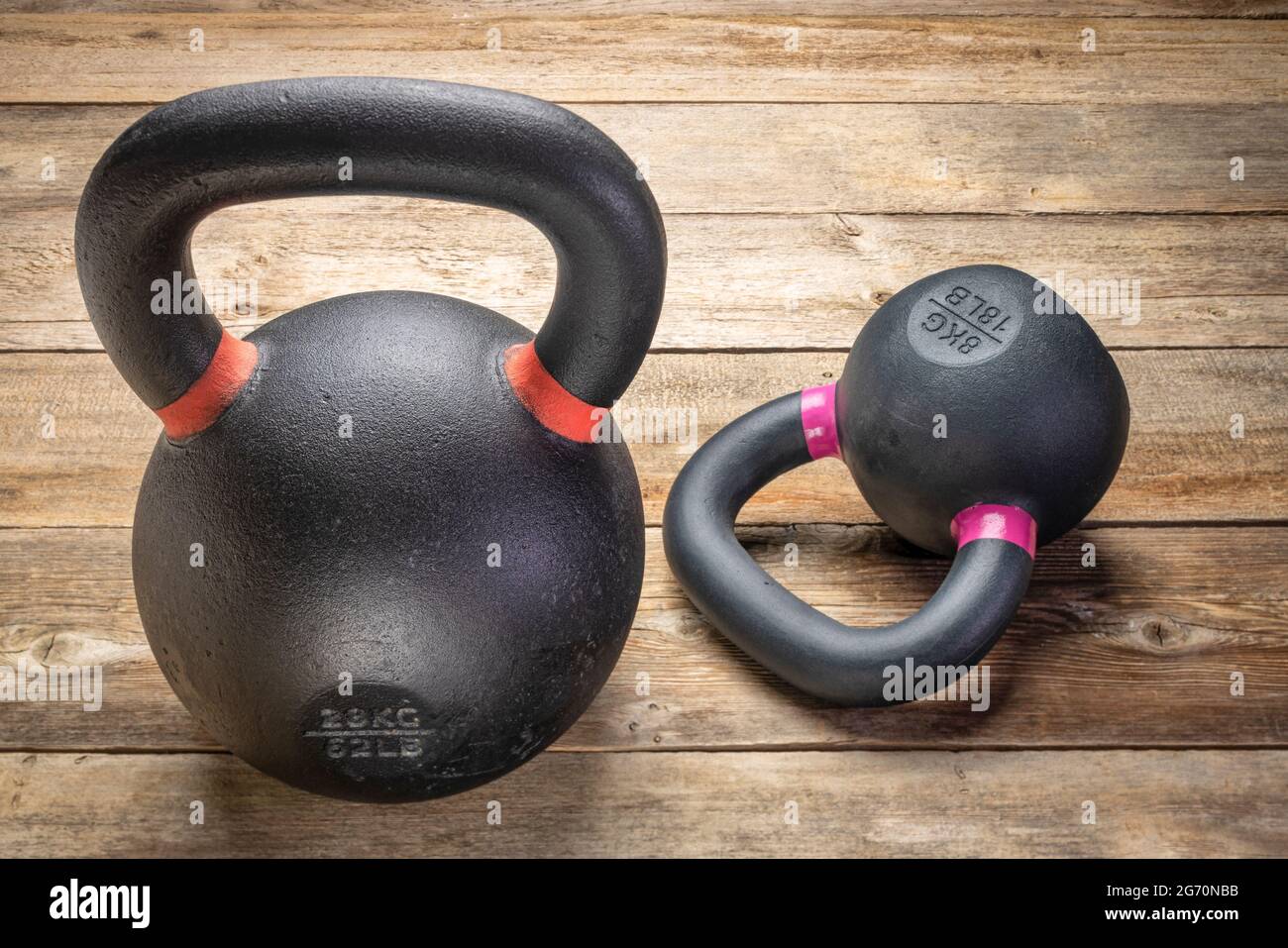 two heavy iron kettlebells on a rustic wood background, weight training ...