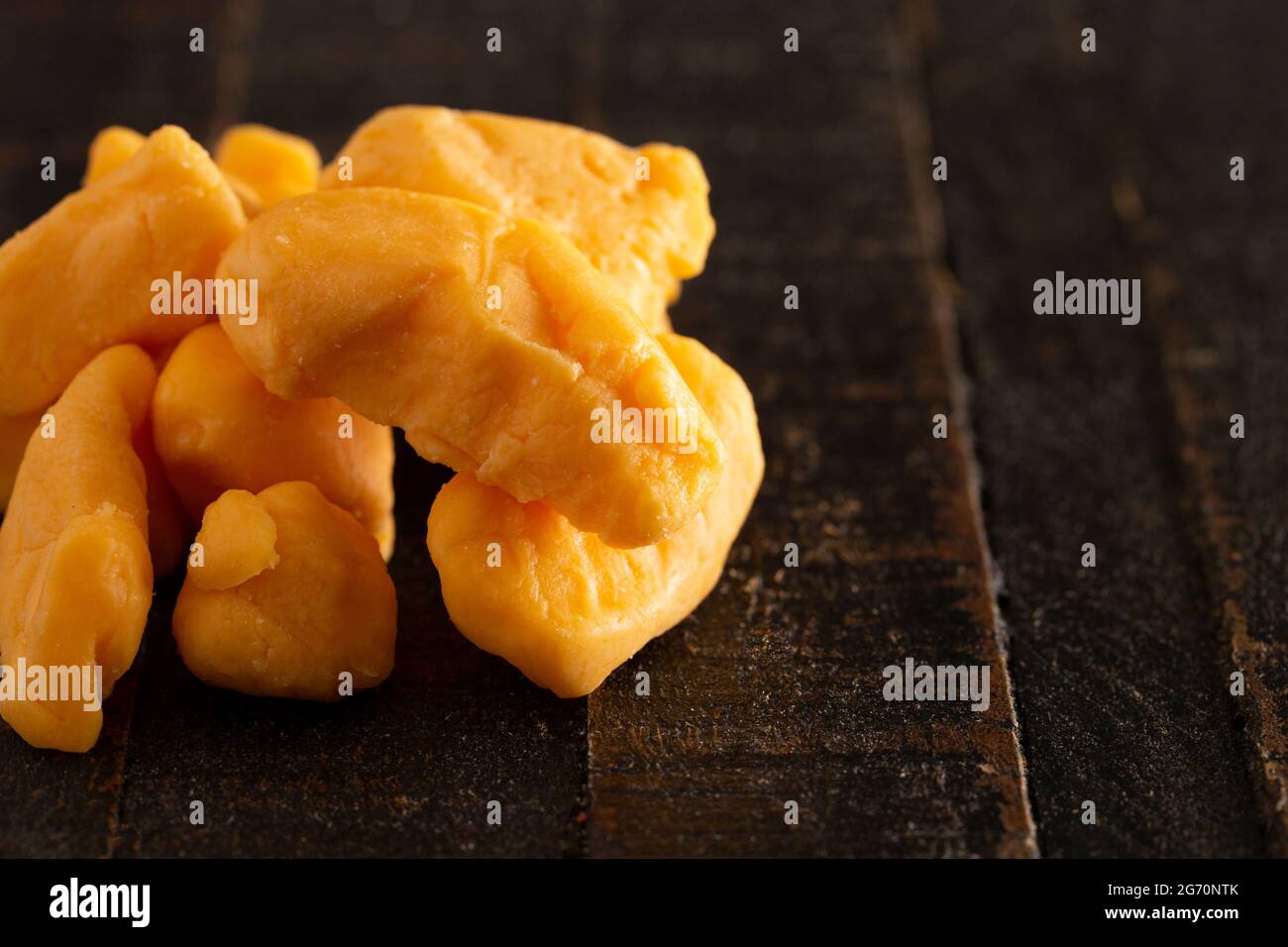 A Pile of Cheddar Cheese Curds on a Rustic Wooden Table Stock Photo - Alamy