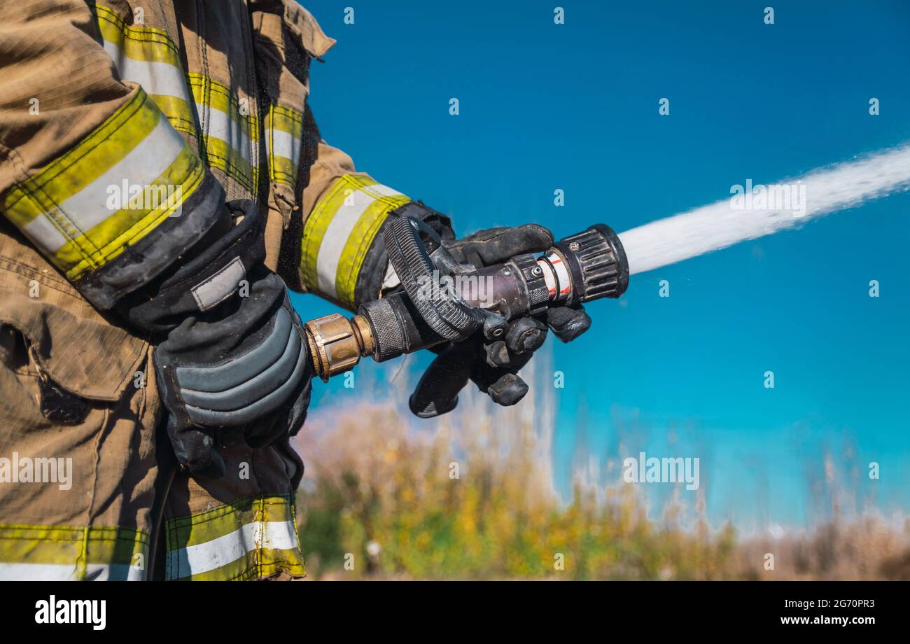 Closeup of a firefighter's hands holding a hose and opening high ...