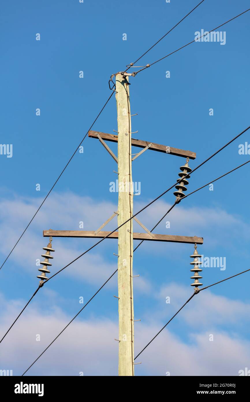 Photograph of a wooden telephone post and cables against a blue sky ...