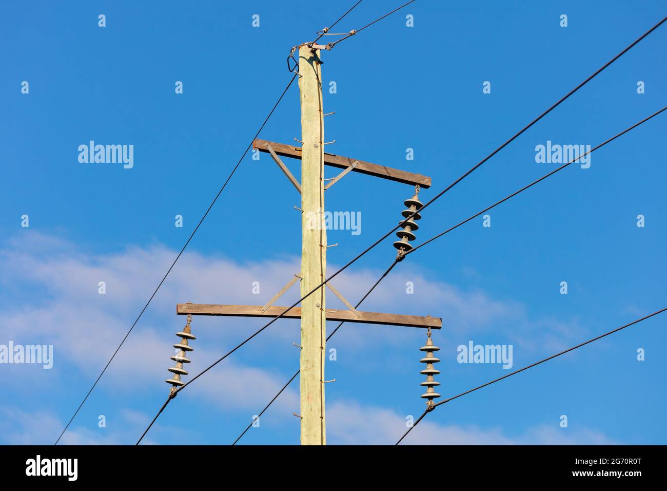 Photograph of a wooden telephone post and cables against a blue sky ...