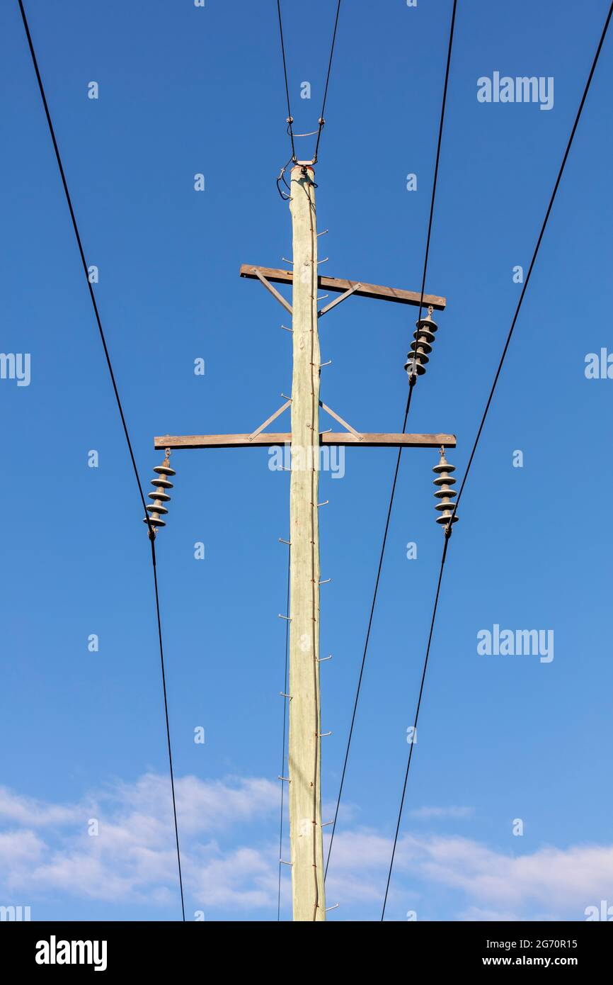 Photograph of a wooden telephone post and cables against a blue sky ...