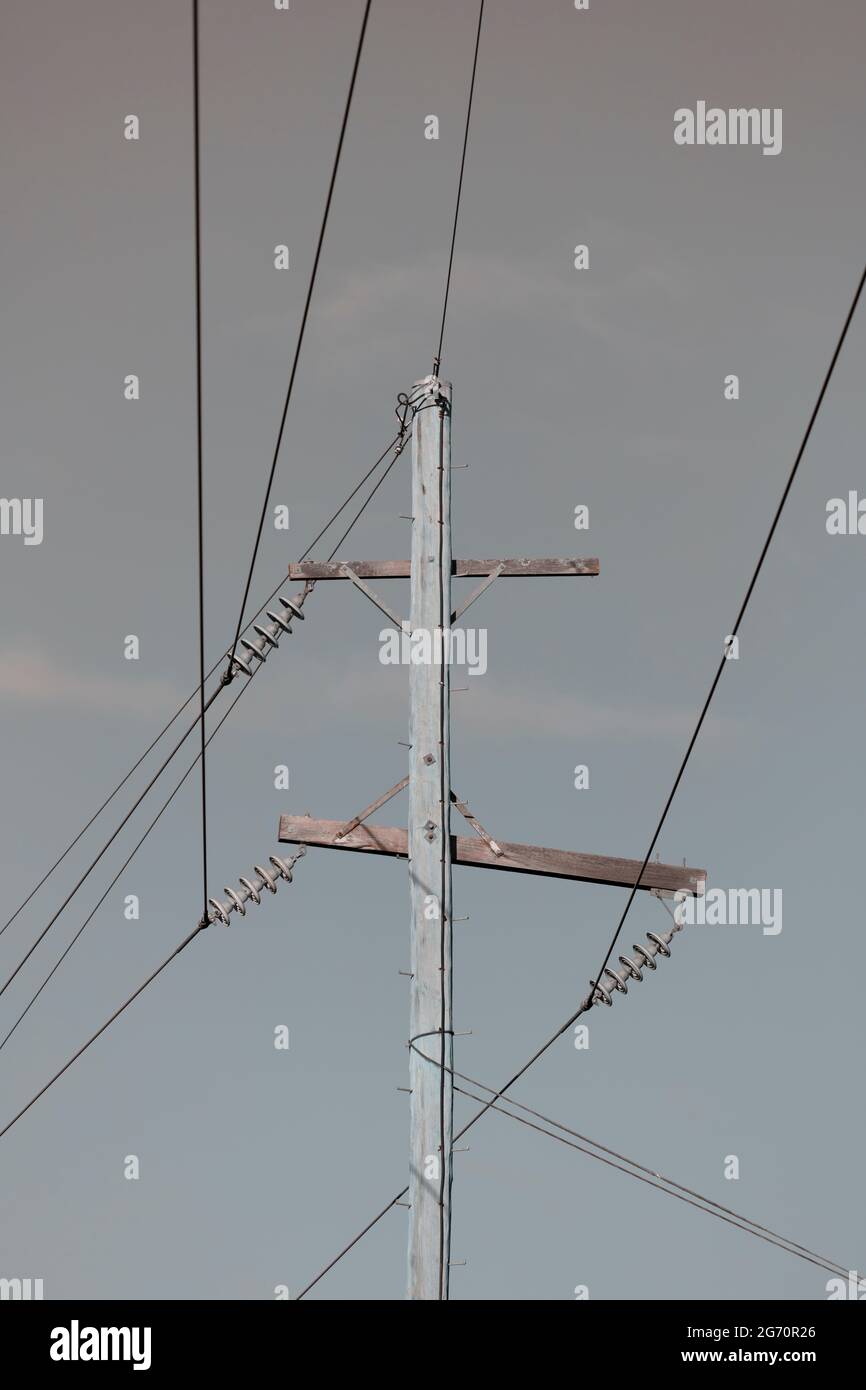 Photograph of a wooden telephone post and cables against a blue sky ...