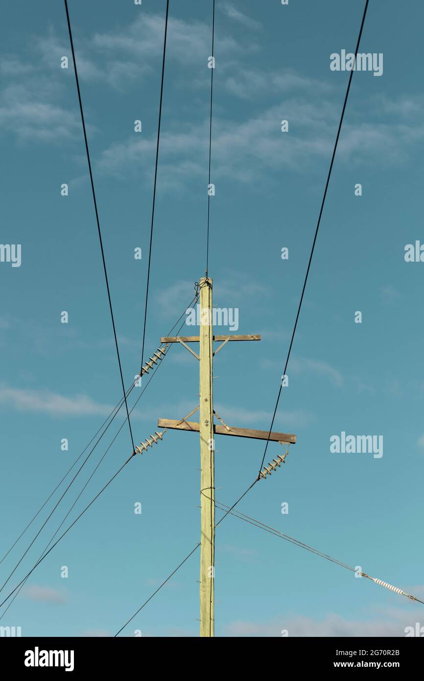 Photograph of a wooden telephone post and cables against a blue sky ...