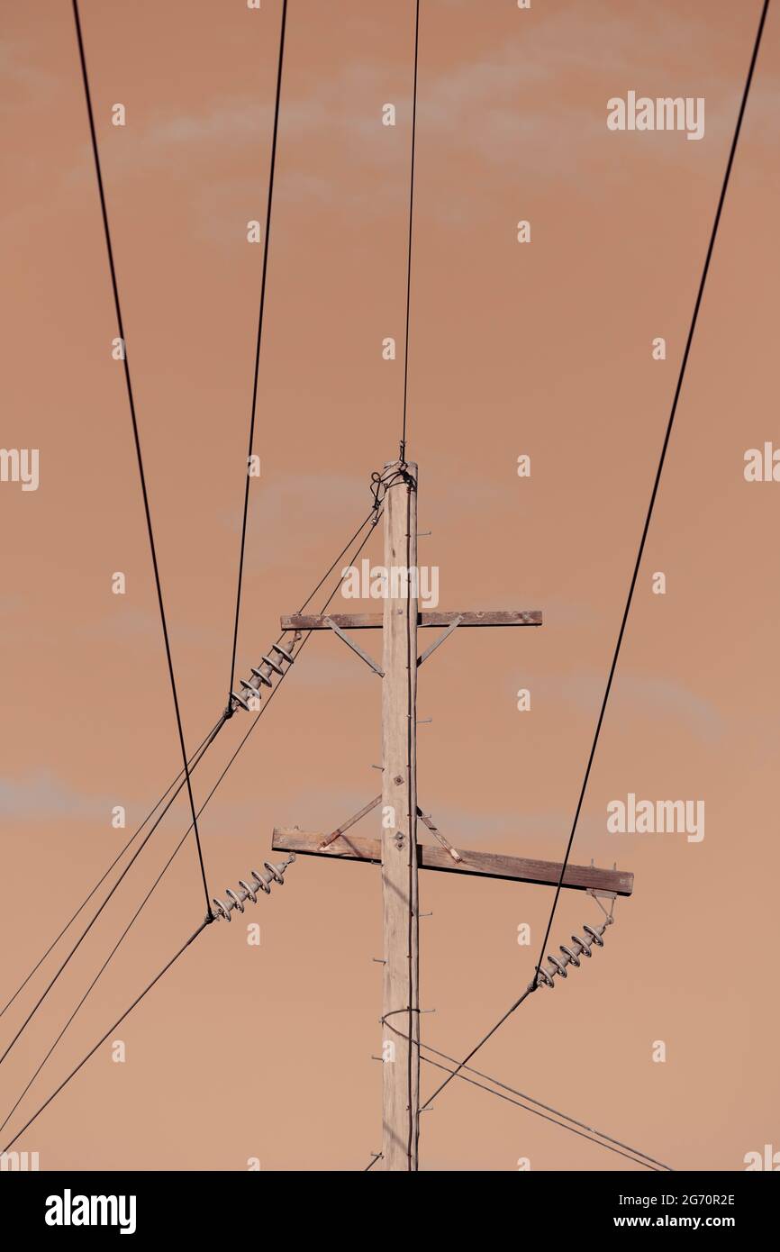 Photograph of a wooden telephone post and cables against a blue sky ...