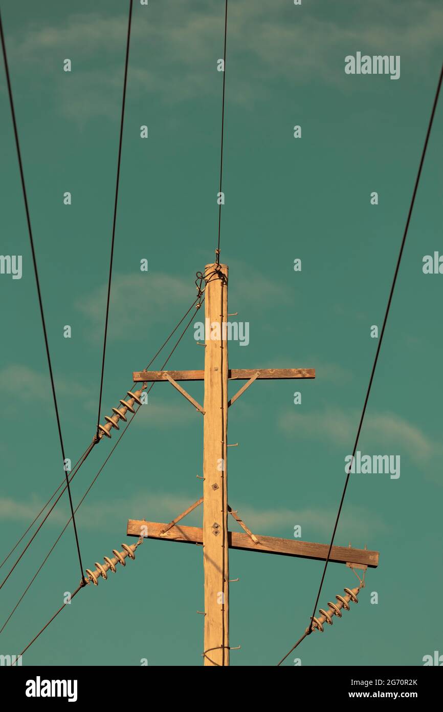 Photograph of a wooden telephone post and cables against a blue sky ...