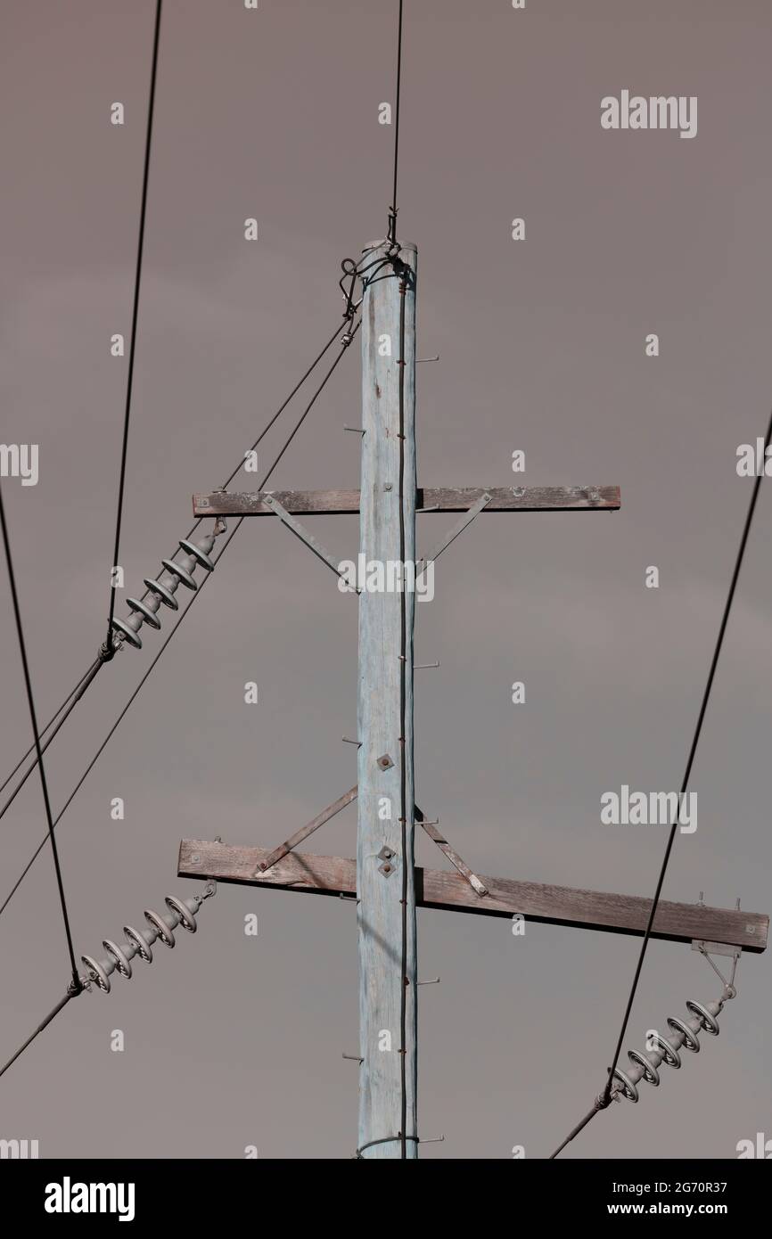Photograph of a wooden telephone post and cables against a blue sky ...