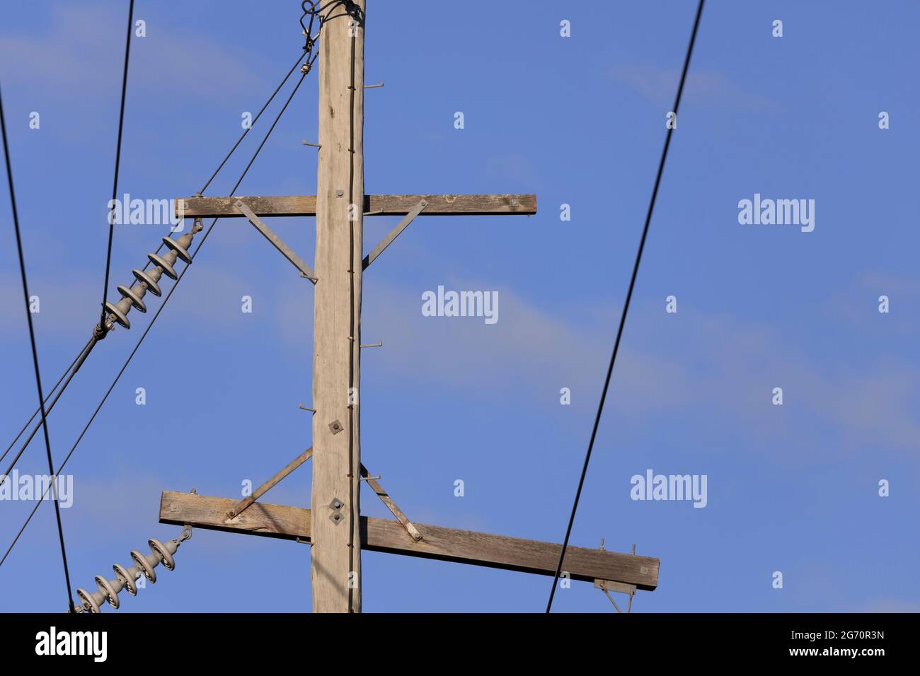 Photograph of a wooden telephone post and cables against a blue sky ...