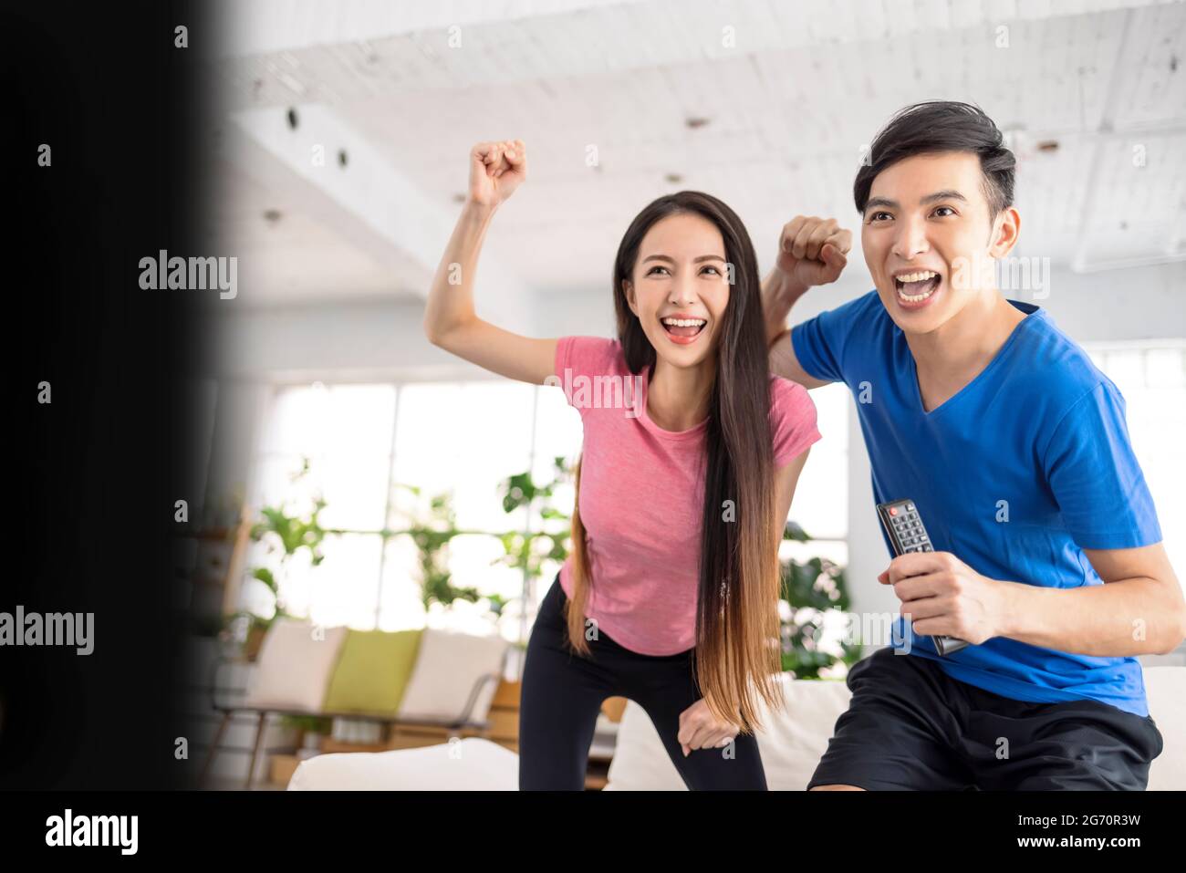 Excited Young Couple watching sports game on tv and having fun at home ...