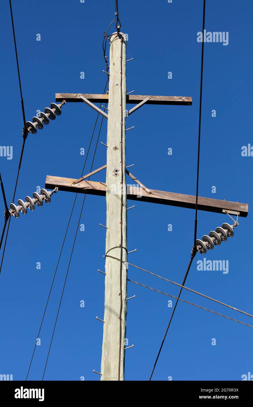 Photograph of a wooden telephone post and cables against a blue sky ...