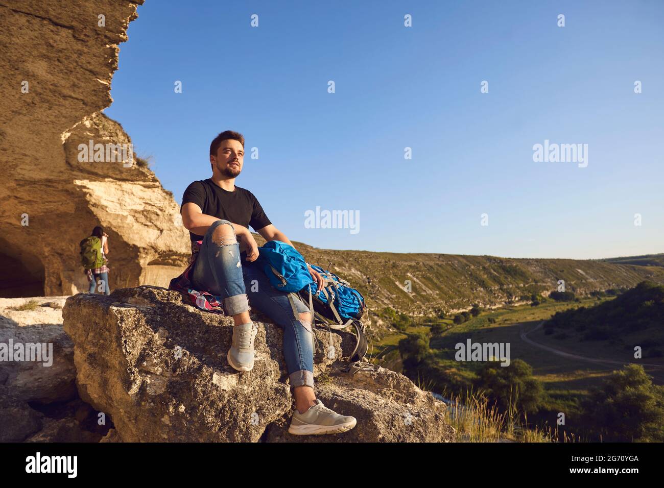 Young hiker sitting and having rest on natural rocks with his group at ...