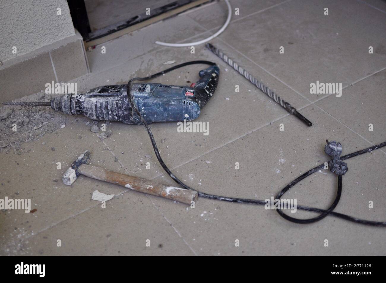 Hammer, chisel and electric drill lying on the tile floor. Renovation ...