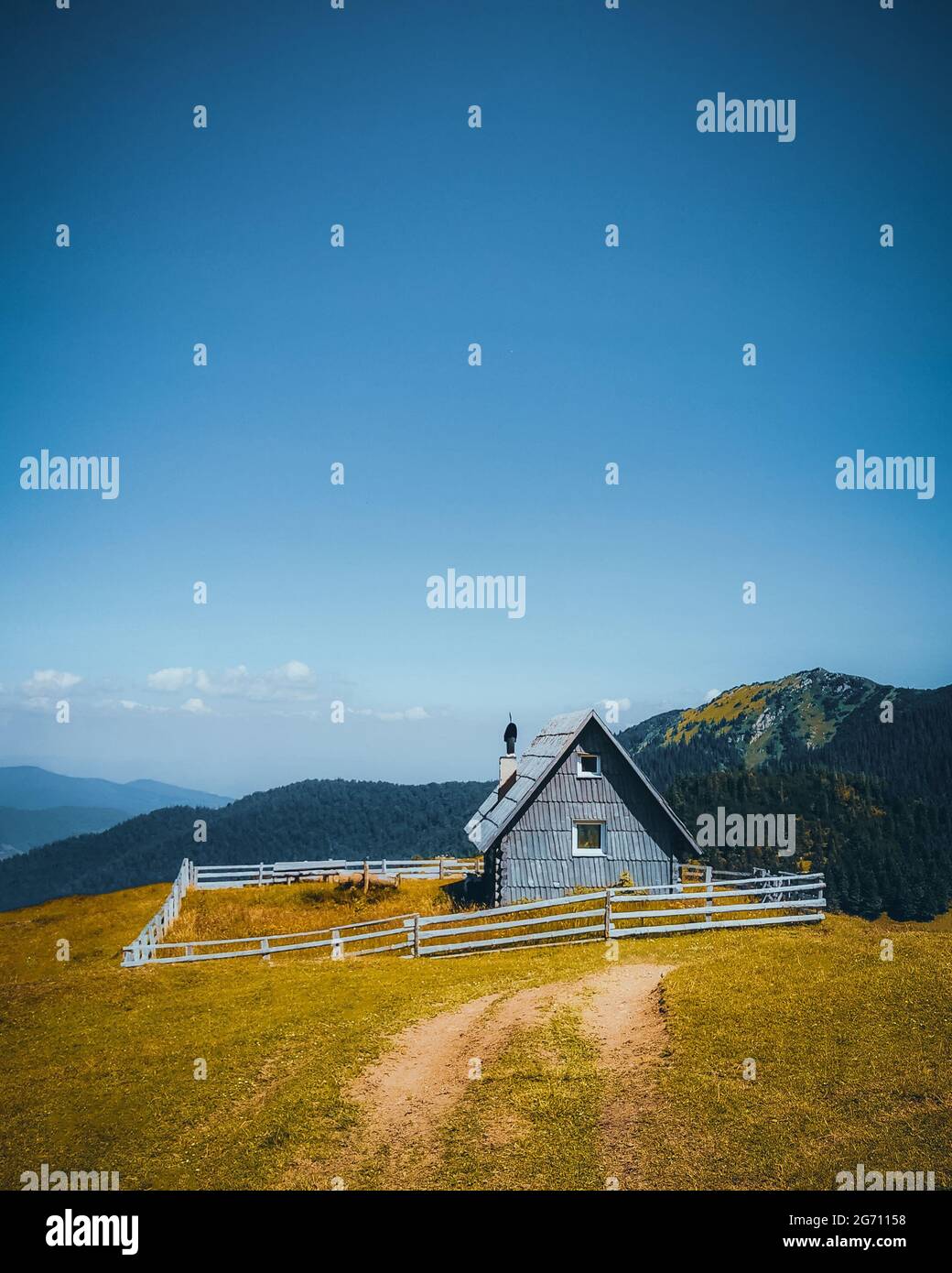 Yellow field with a fenced house in mountains under clear sky Stock ...