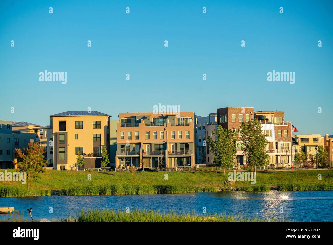 Tree buildings with grassland and a like against them under the clean ...