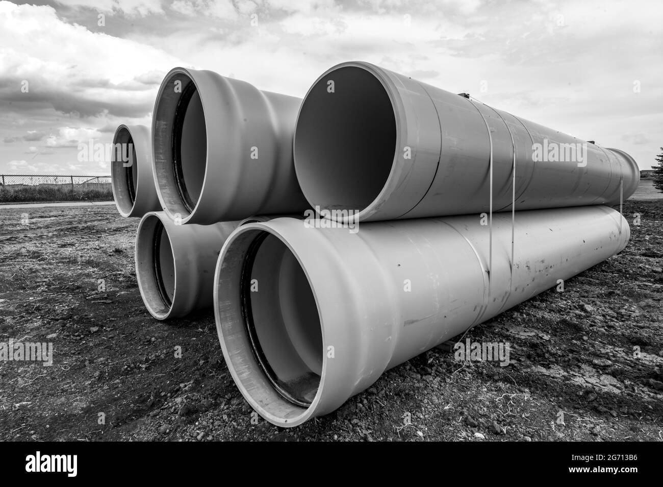 Stacked water main pipe with bell fitting next to an exposed trench for ...