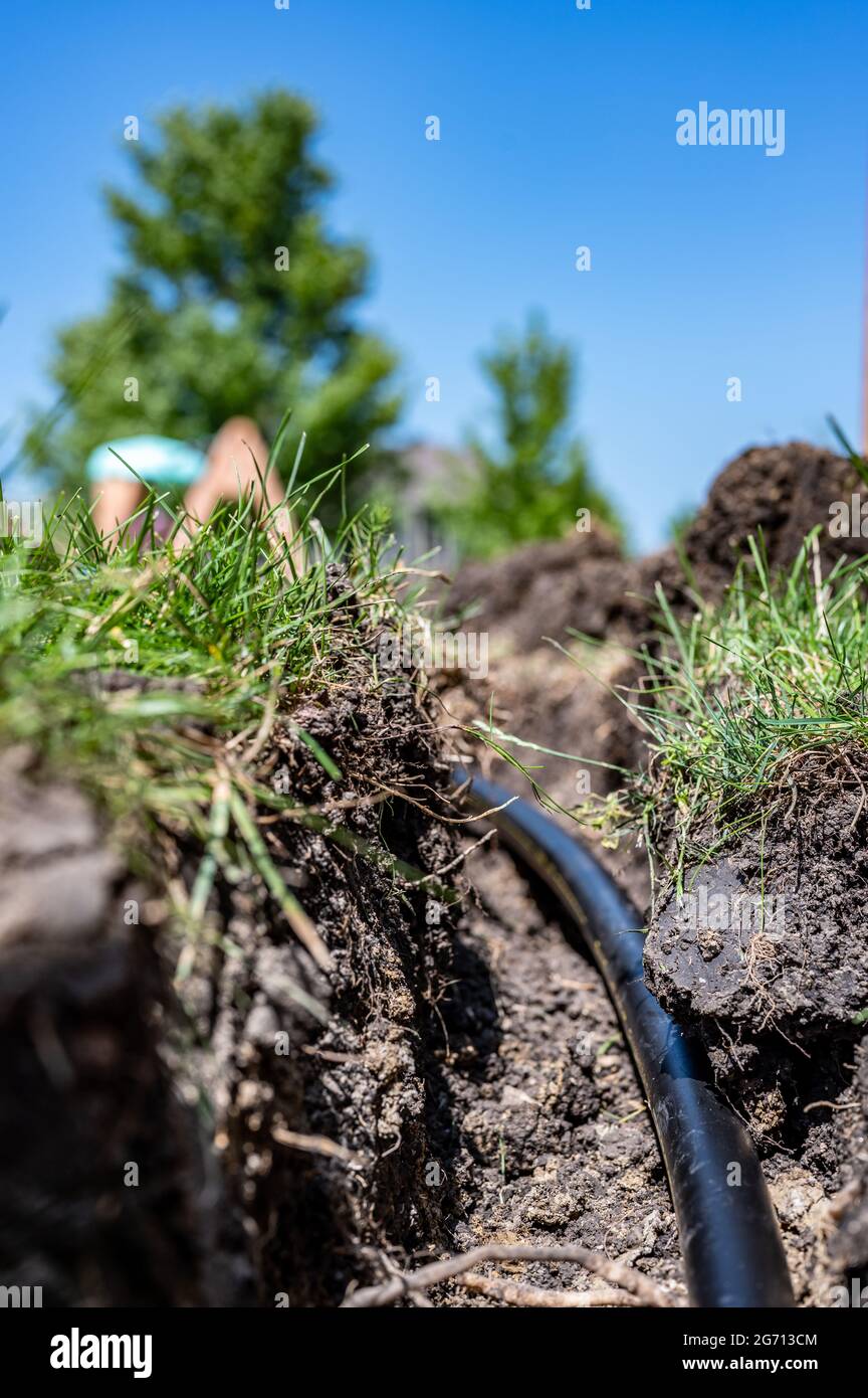 Focus on a black 1 inch sprinkler plastic water line laid in a shallow ...