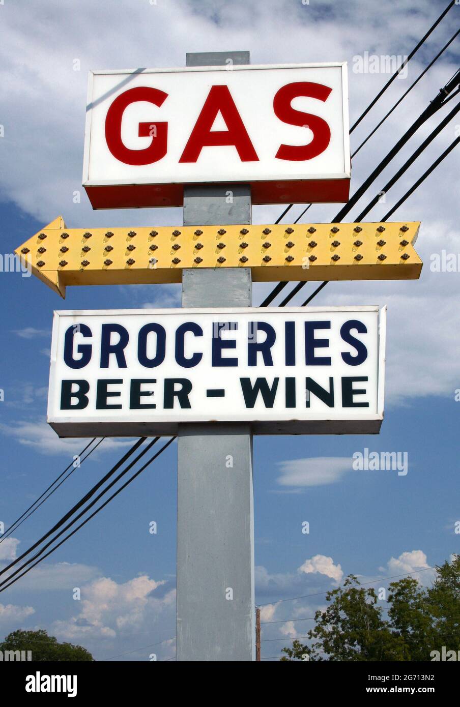 Vertical shot of a sign saying "gas" above a yellow arrow pointing left ...