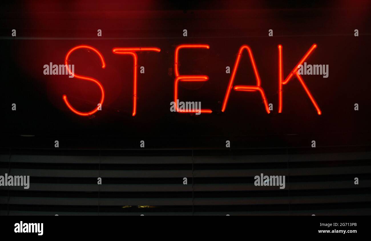 Word steak in glowing red neon text on a restaurant wall ...
