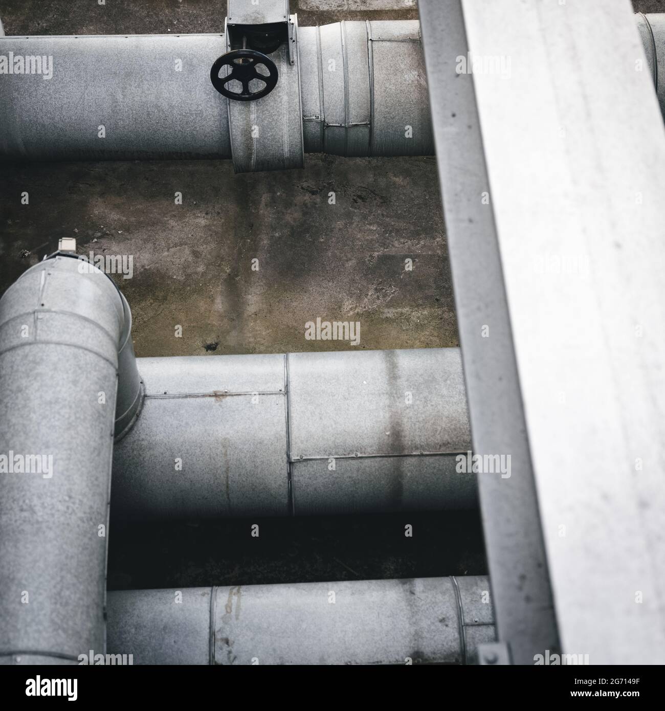 Overhead of huge white pipes of water with black valve Stock Photo - Alamy