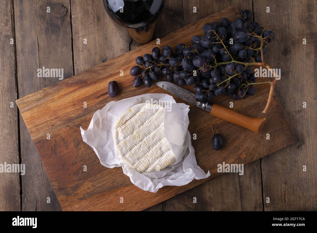 Round piece of cheese wrapped in a white napkin on a wooden board and ...