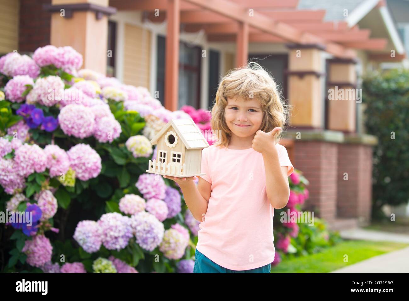 Child with toy small houses in hands outdoor. Cute kid playing with ...