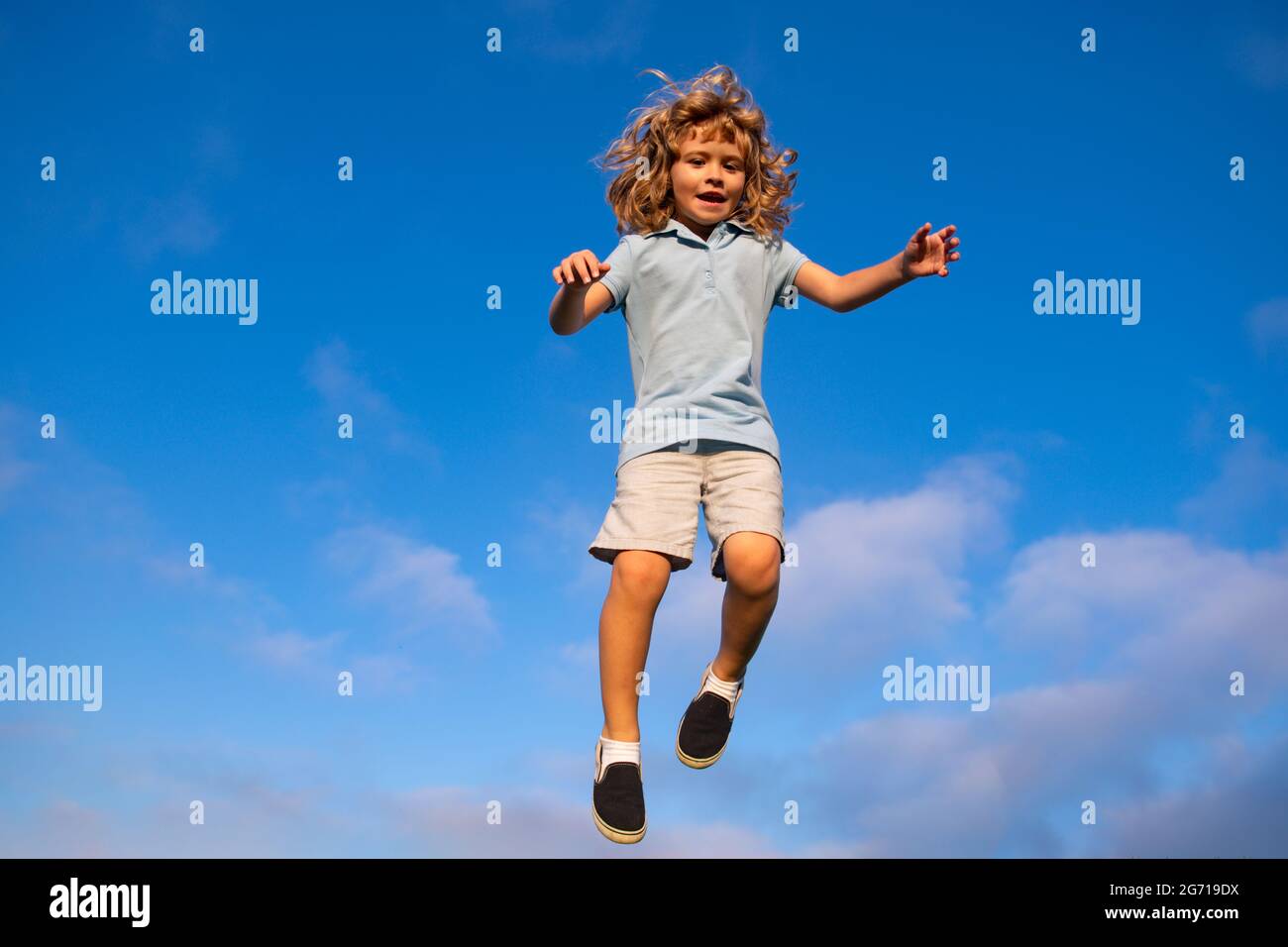 Caucasian boy in a park running and smiling on blue sky. Happy kid ...