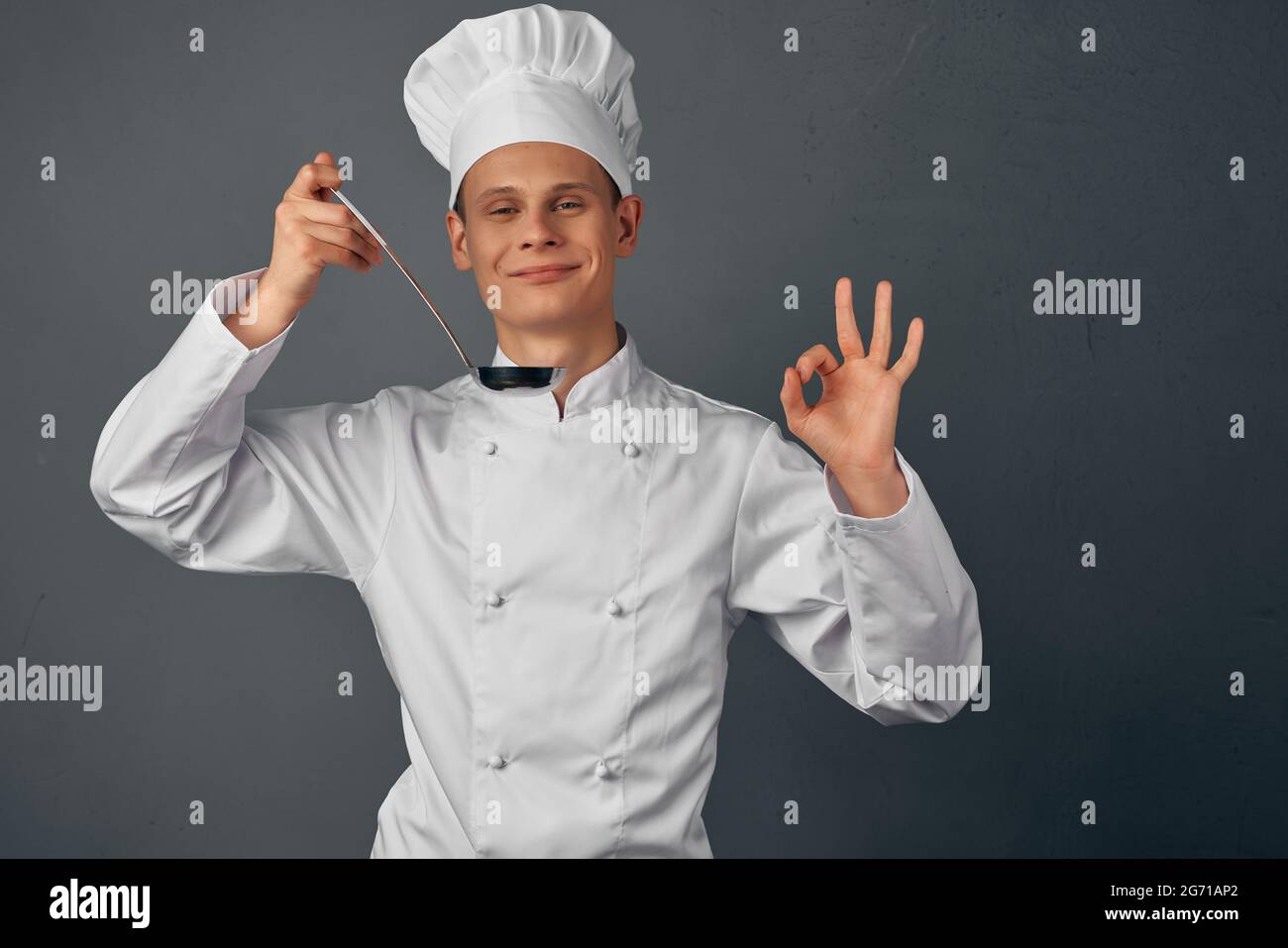 chef in a white robe with a ladle in his hands cooking food restaurant ...