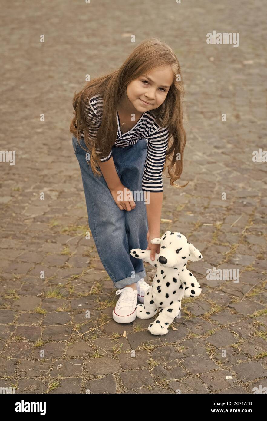 Every toy has spirit of joy. Happy child play with soft dog outdoors ...