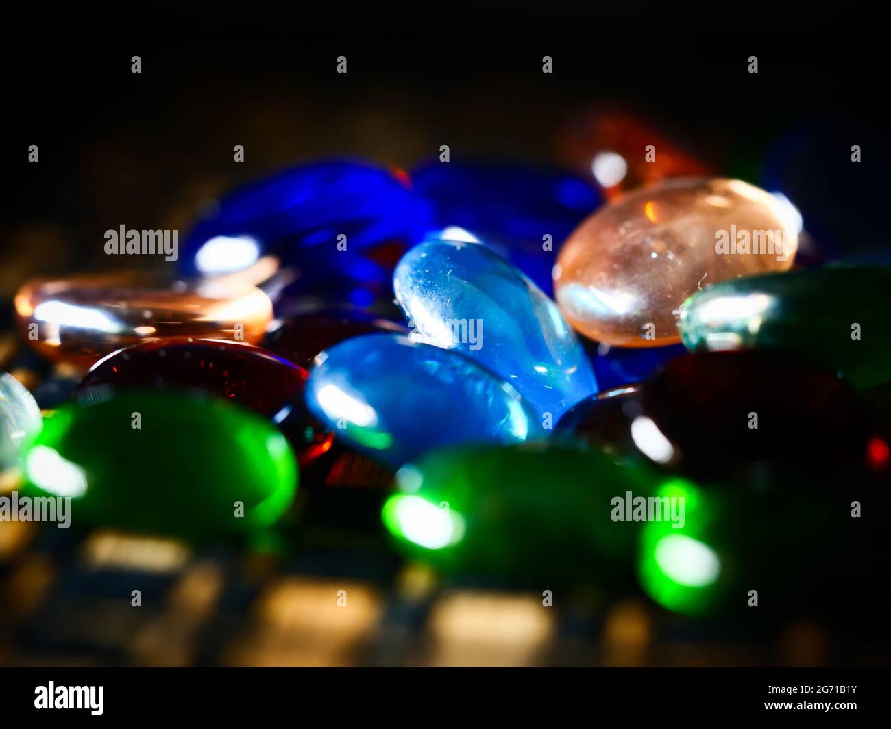 Closeup of shiny reflective glass gems with a blurred black background ...
