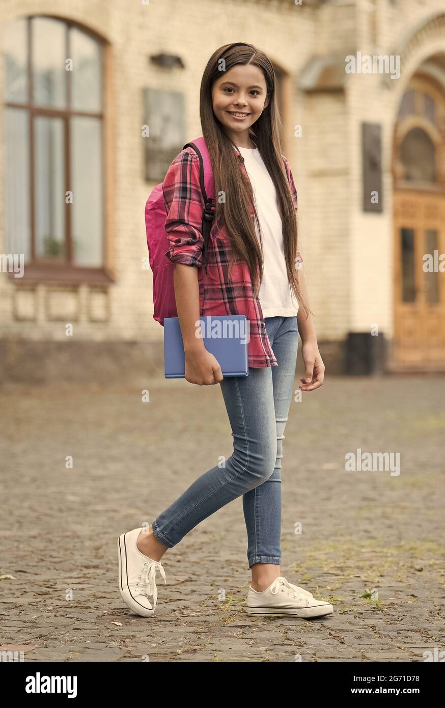 Ready for studies. Happy child carry bag and book in schoolyard. Back ...