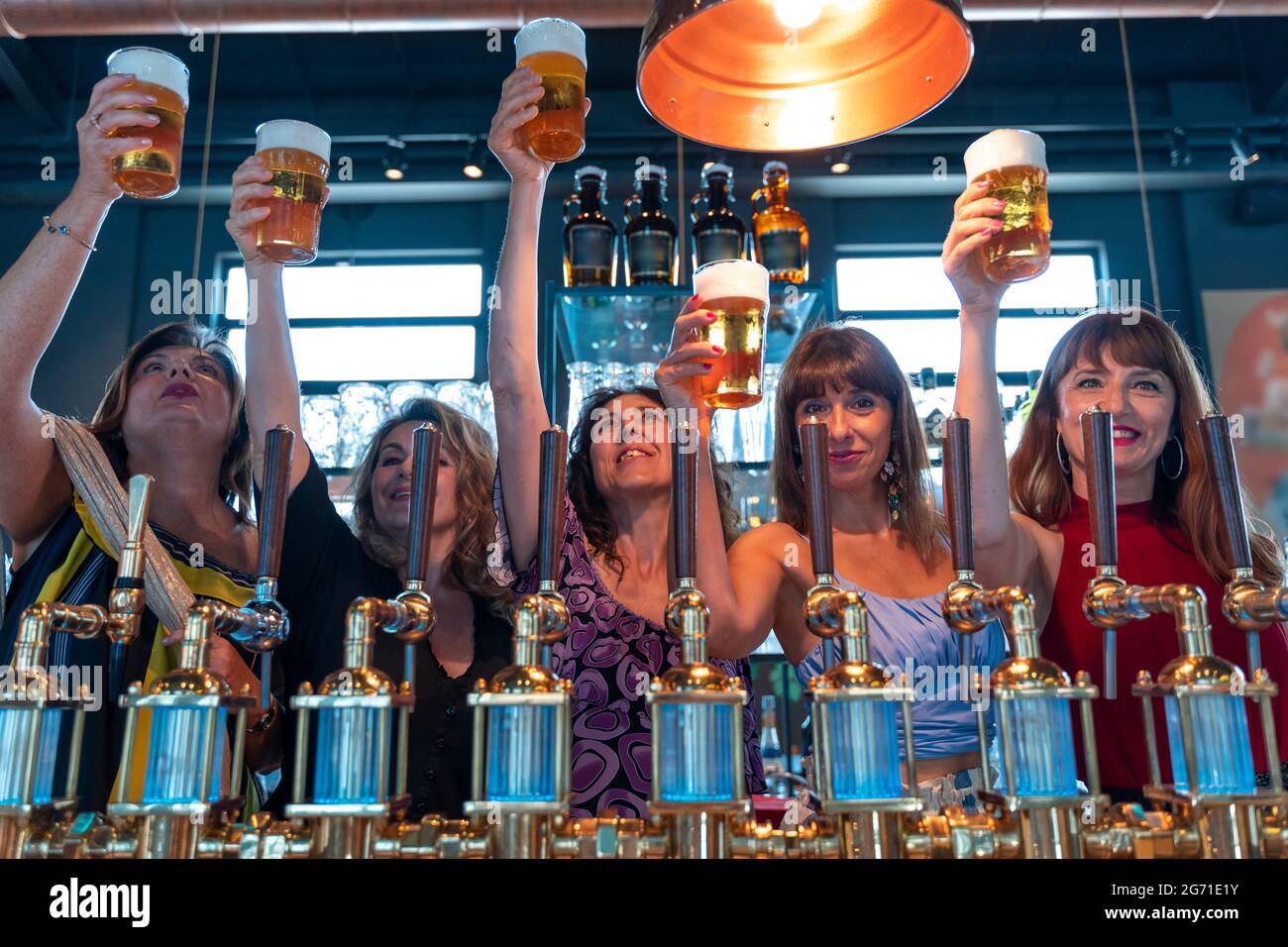 group of mature women is drinking beer in a pub in front of a beer tap ...