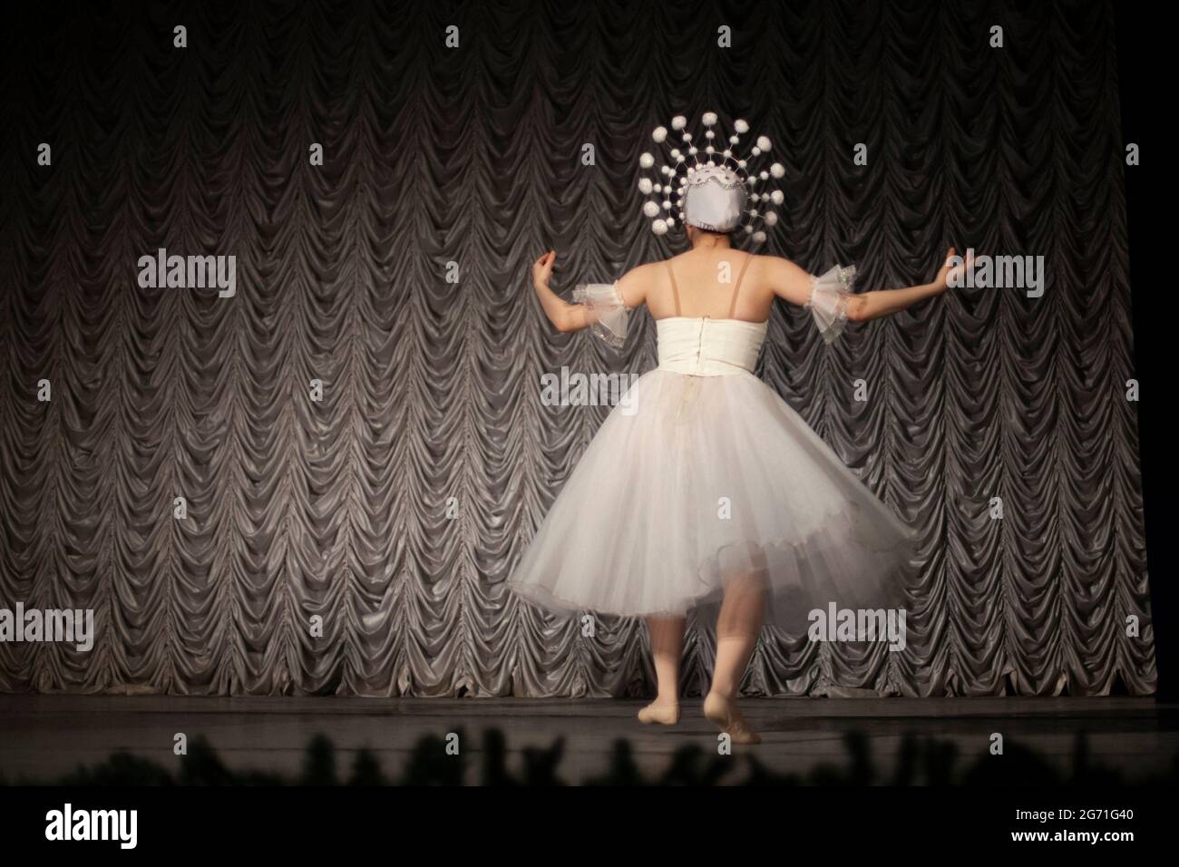 The girl is dancing on stage in a white dress. The artist is performing ...