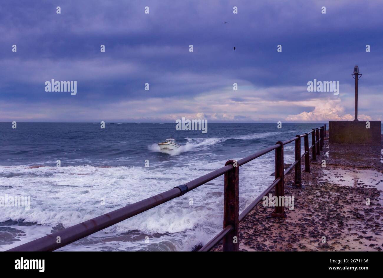 Fishing motor boat coming into shore at Port Alfred on a cold stormy ...