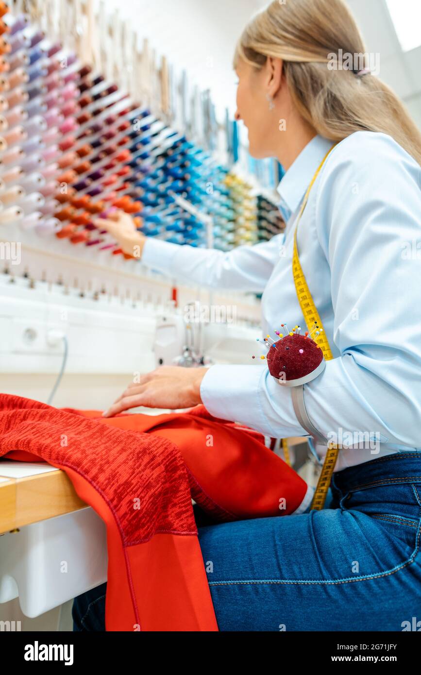 Close-up on the hand and works of an alterations tailor at her sewing ...