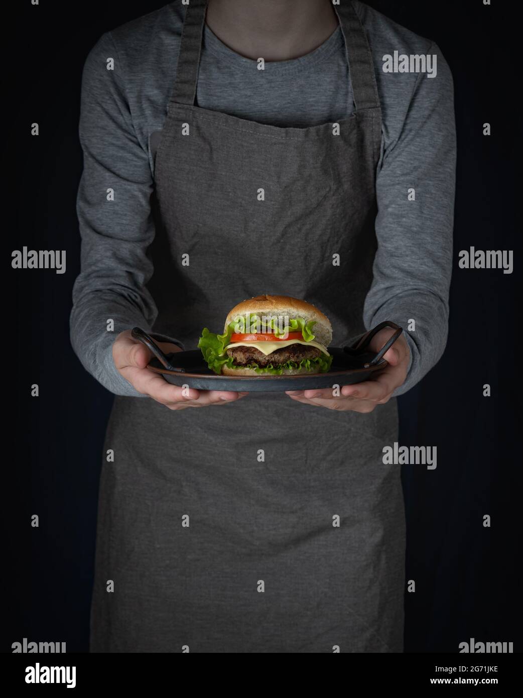 Woman in apron holding in her hands a tray with burger Stock Photo - Alamy