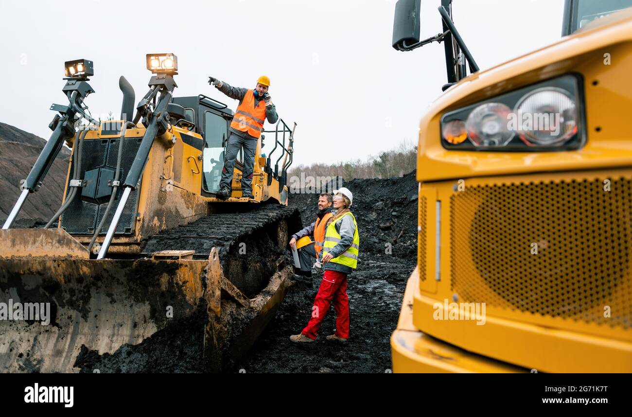 Heavy machinery and workers in pit of quarry shouting at each other ...