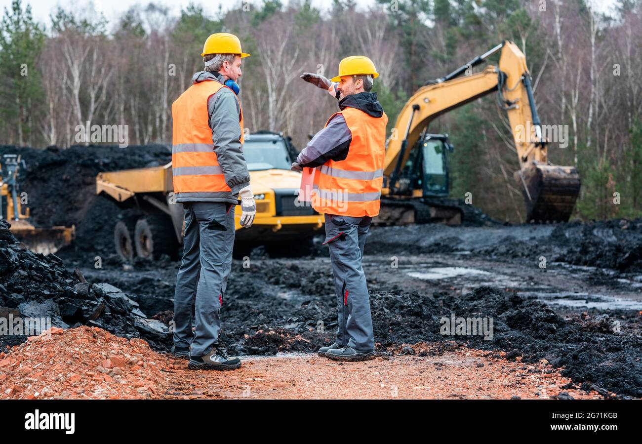 Two quarry workers discussing what to do next pointing at things Stock ...