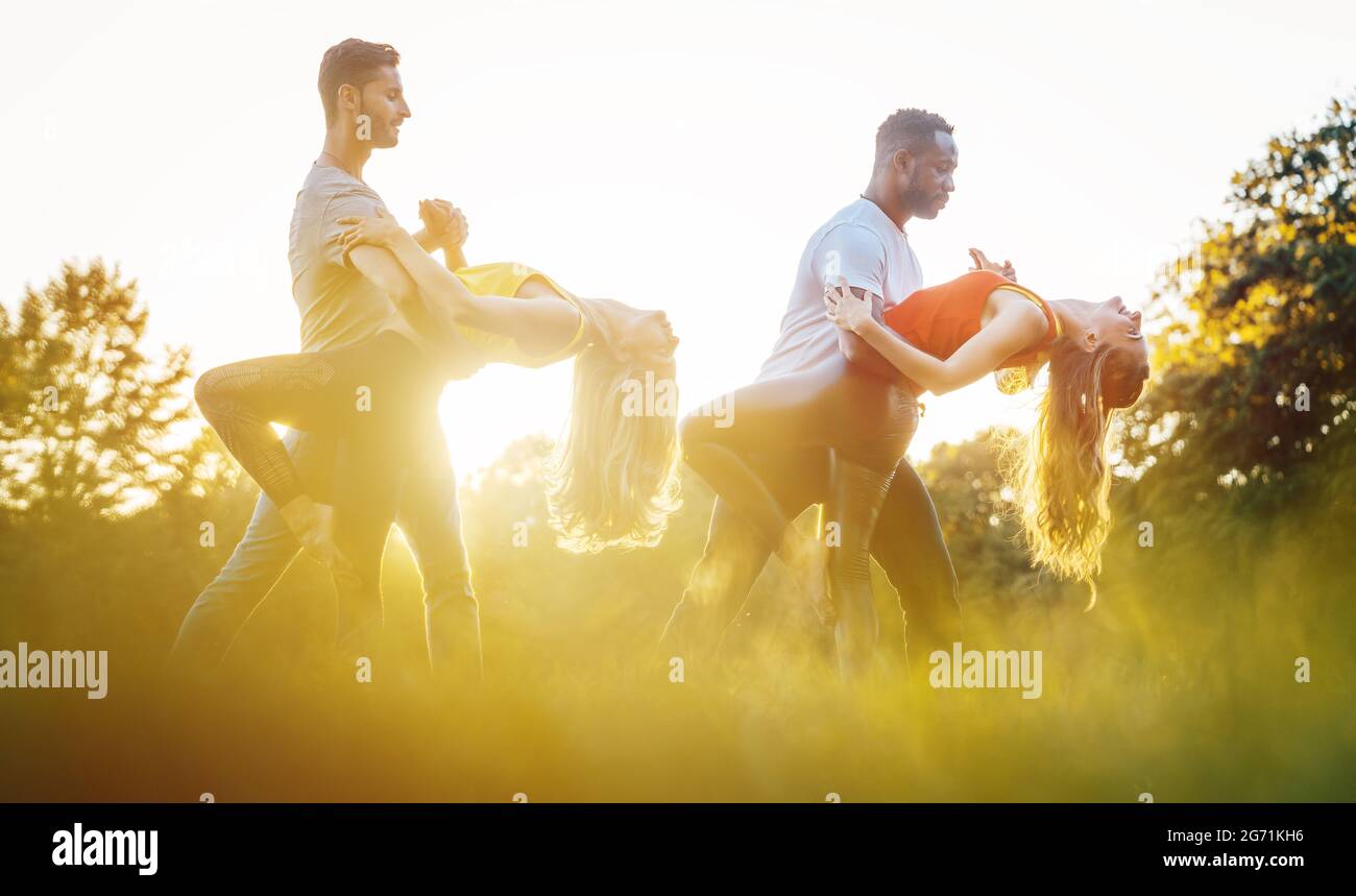 Women and men performing dance moves against backlit park Stock Photo ...