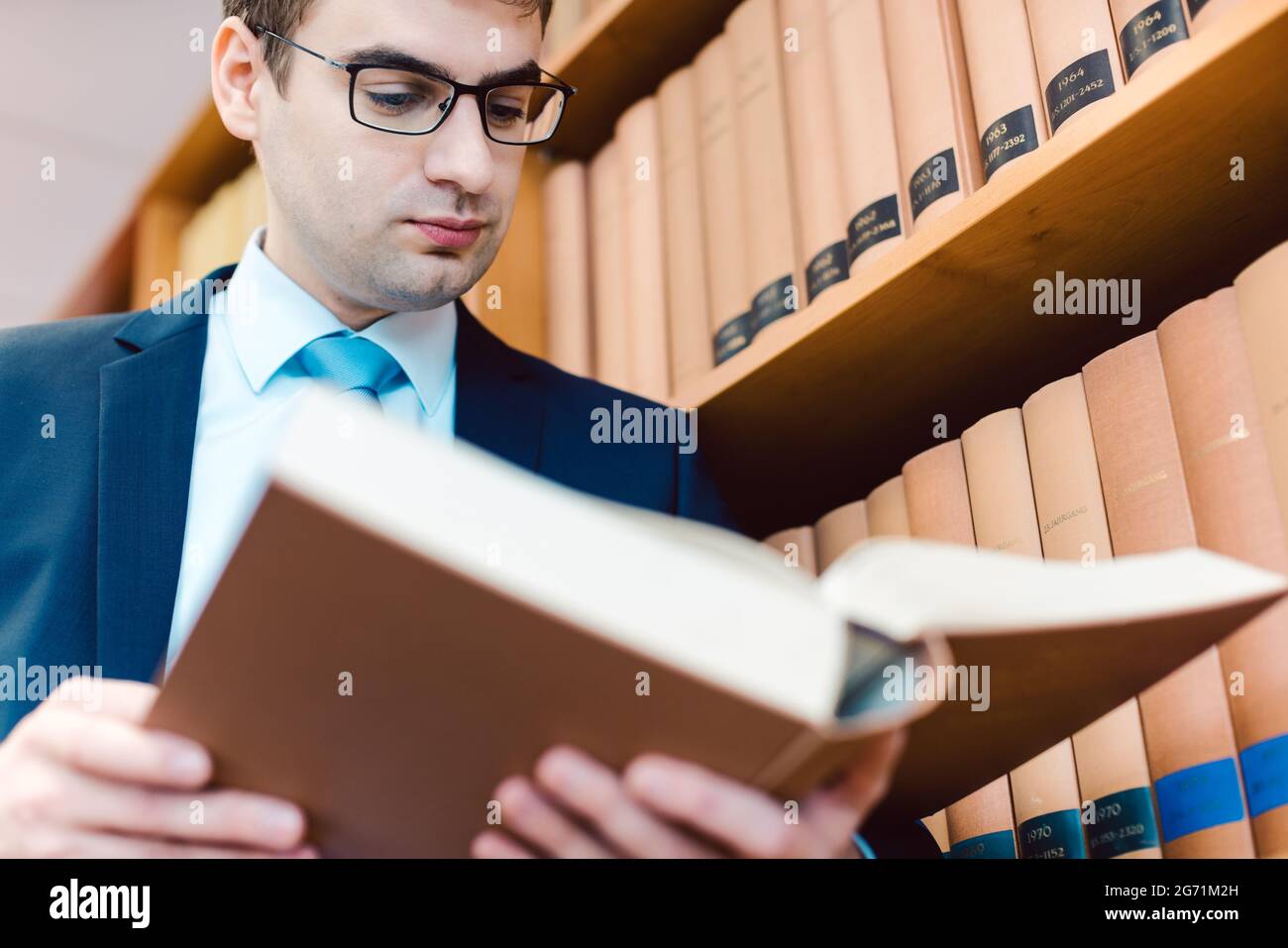Lawyer in his office reading precedents in thick books thinking about a ...