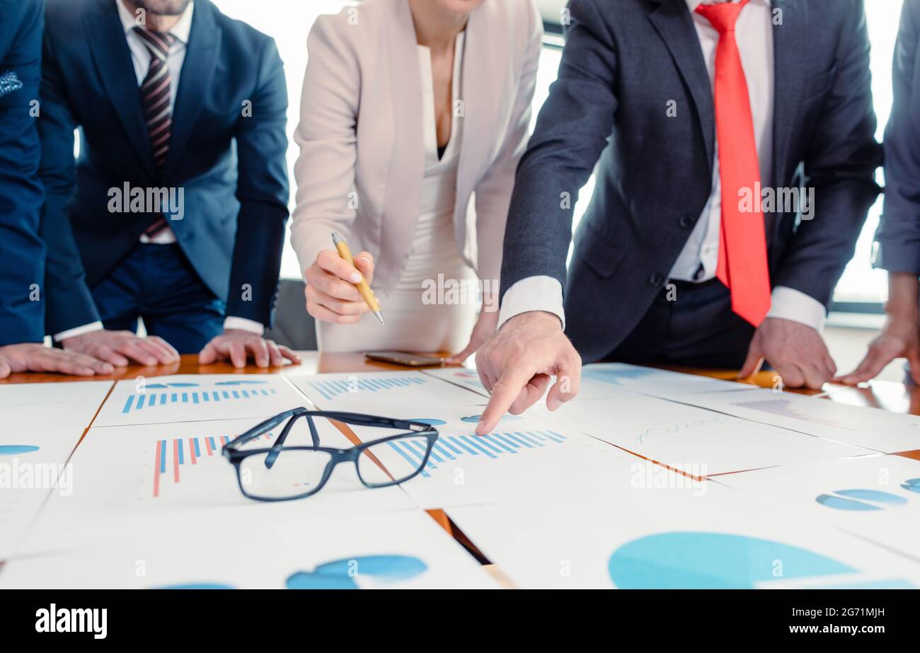 Team of business people analyzing numbers and charts spread out on the ...