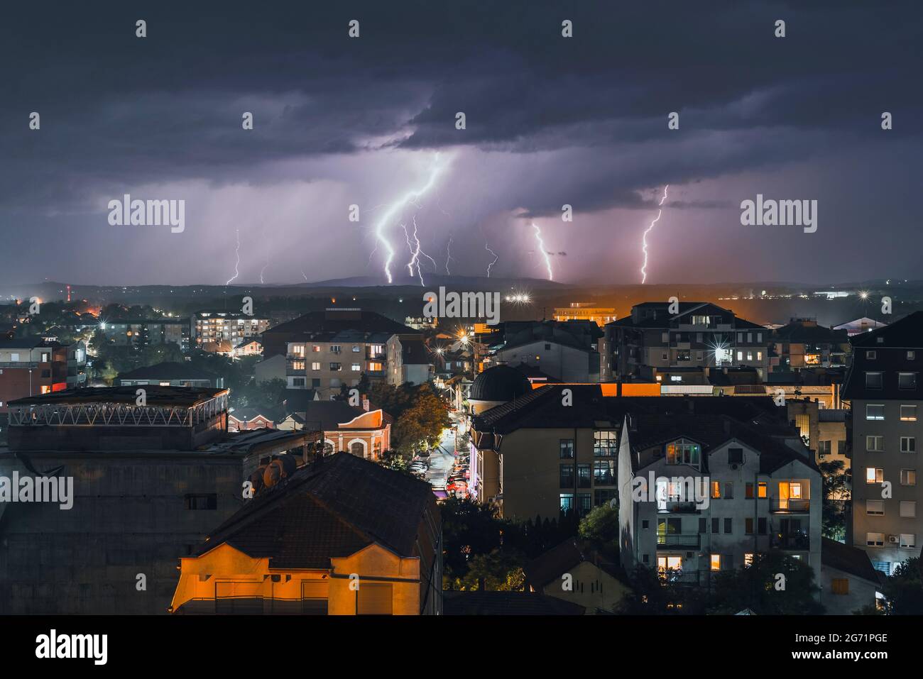 Lightning and thunderstorm in the distance behind small town at night ...