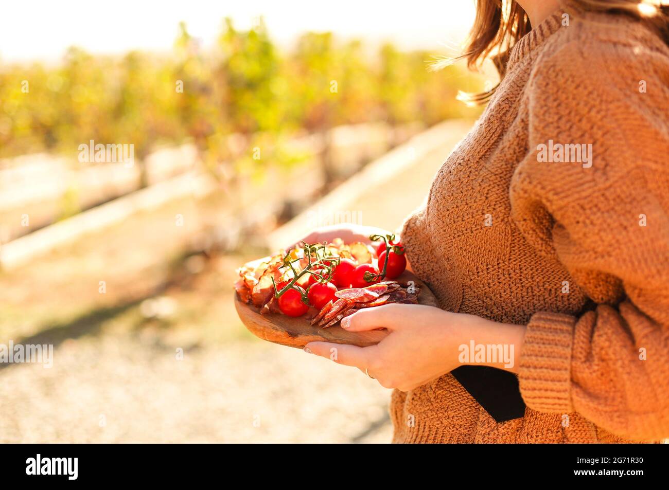 Unrecognizable woman carrying board with slices of ham and ripe cherry ...